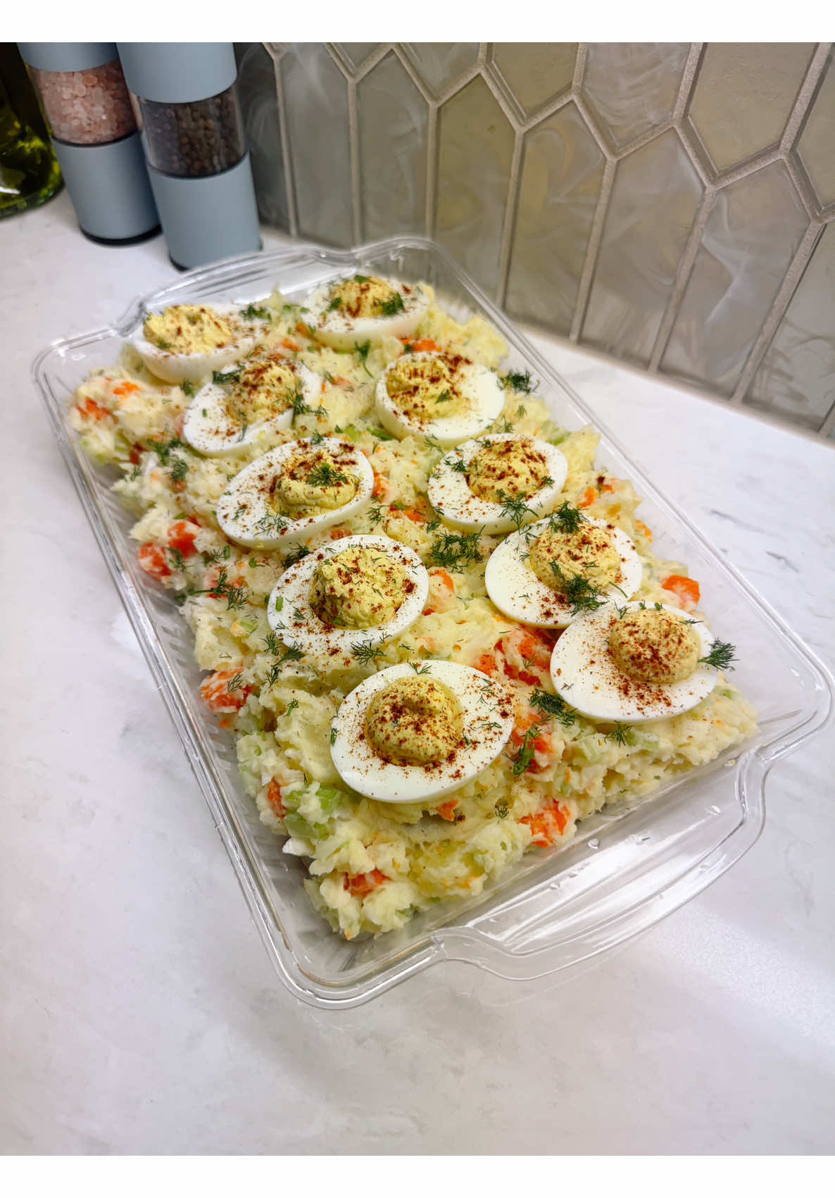 Making creamy potato salad alongside deviled eggs dusted with paprika ...